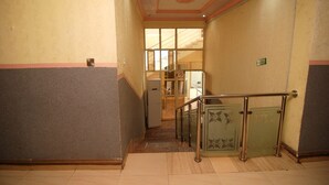 Um corredor com porta de vidro dando para uma escada, sinal de saída de incêndio e parede com padrão.