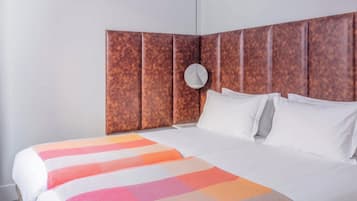 Quarto de hotel com uma cama, cabeceira e espelho redondo fixado na parede.
