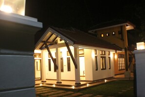 Um edifício de dois andares com varanda coberta e entrada bem iluminada.