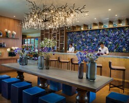 Um restaurante com um balcão comprido, banquetas azuis e um candelabro.
