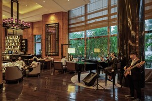 Ampla área de estar com piano, mesa de bilhar e bar com prateleiras cheias de garrafas.