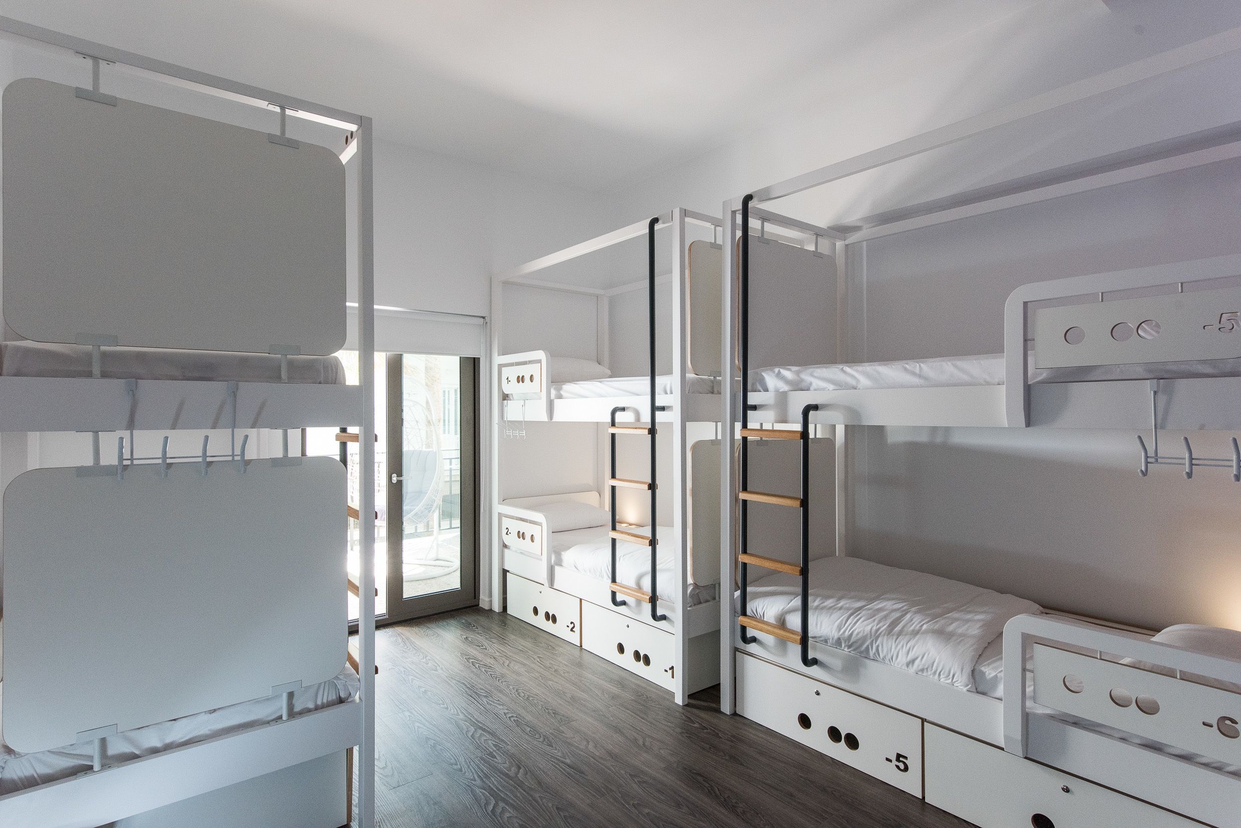 Quarto moderno e bem iluminado, com beliches, escrivaninha e janela que oferece luz natural.