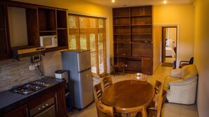 Uma cozinha compacta com fogão a gás, micro-ondas, frigorífico e armários de madeira.