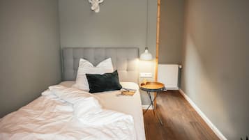 Quarto com cama, mesa de cabeceira, luminária e um chifre de veado fixado na parede.