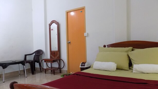 Quarto com cama de madeira, uma cadeira, escrivaninha e espelho.