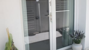 Entrada de um edifício moderno, com porta de vidro e um vaso com planta no chão.