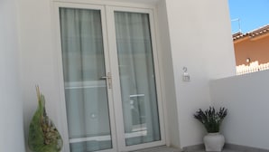 Entrada de um edifício com porta de vidro, planta em vaso e uma pequena placa.