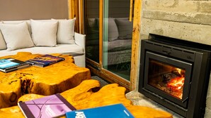 Um quarto aconchegante com lareira, um sofá e uma mesa de centro com livros.
