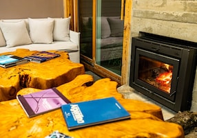Um quarto aconchegante com lareira, um sofá e uma mesa de centro com livros.