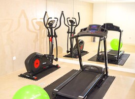 Uma academia com esteiras, elípticos e bolas de exercícios.