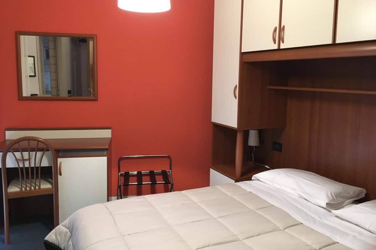 Quarto com cama, escrivaninha, cadeira e guarda-roupa.