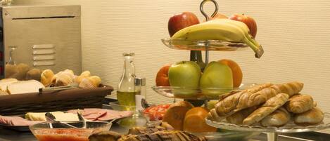 Buffet com diversas opções de comida, incluindo frutas, doces e pão.