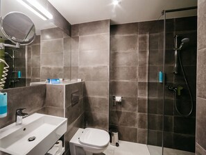Uma casa de banho moderna com lavatório, sanita e chuveiro.