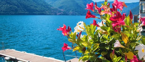 Um píer de madeira que se estende por um lago, com montanhas ao fundo.