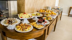 Uma mesa de buffet com diversos alimentos e uma máquina de café.