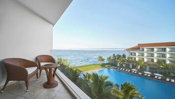 Varanda com mobiliário de vime, vista para piscina e oceano.
