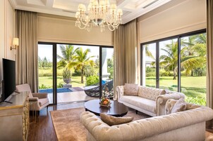 Uma sala de estar espaçosa com uma grande janela, um candelabro e vista para um jardim exuberante.