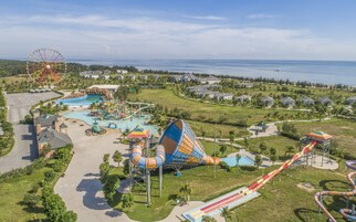 Vista aérea de um parque temático, com um toboágua, roda gigante e uma grande área de piscina.