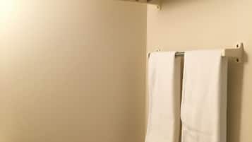 Casa de banho com sanita, um porta-toalhas com toalhas dobradas e um rolo de papel higiénico.