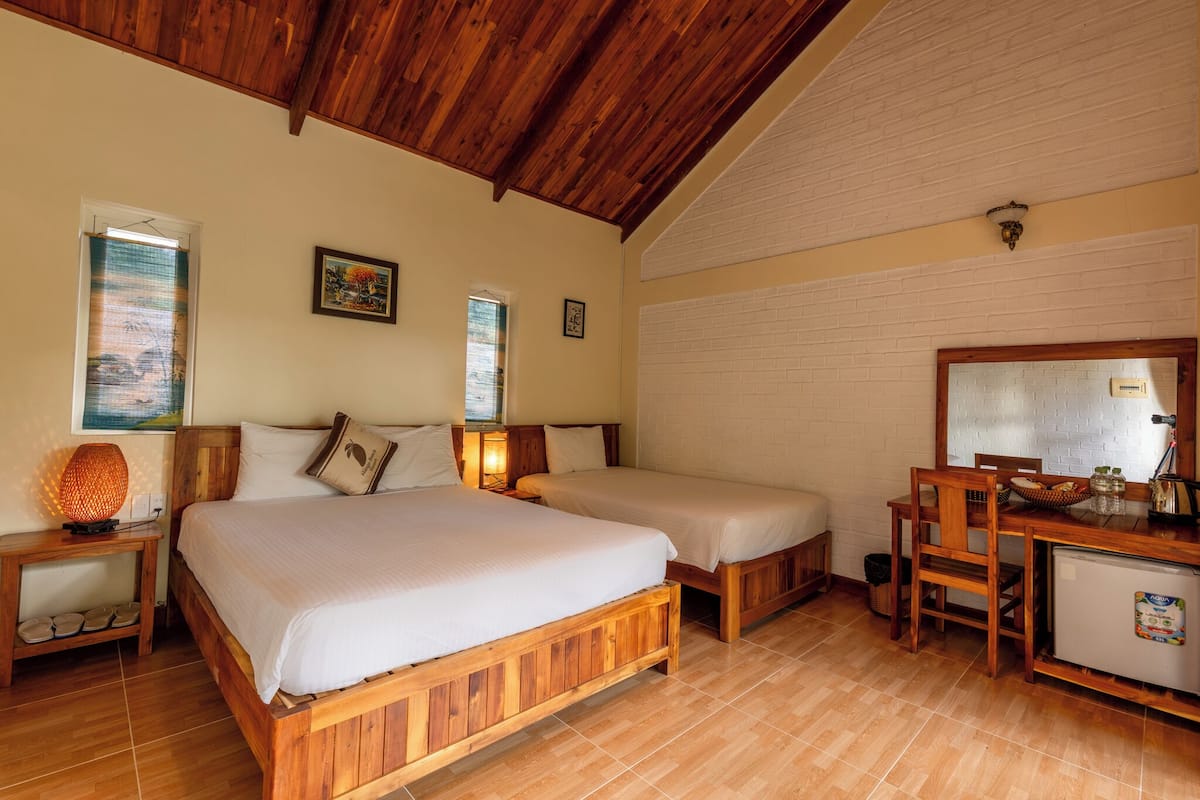 Quarto com uma cama grande, duas camas menores, uma escrivaninha e um frigorífico.