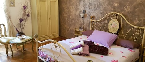 Quarto com uma cama, mesa de cabeceira, cadeira, mesa e guarda-roupa.