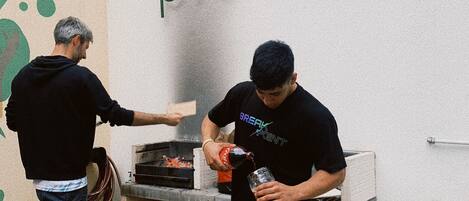 Dois homens num pequeno bar ao ar livre, com um letreiro que diz "pic NIC".