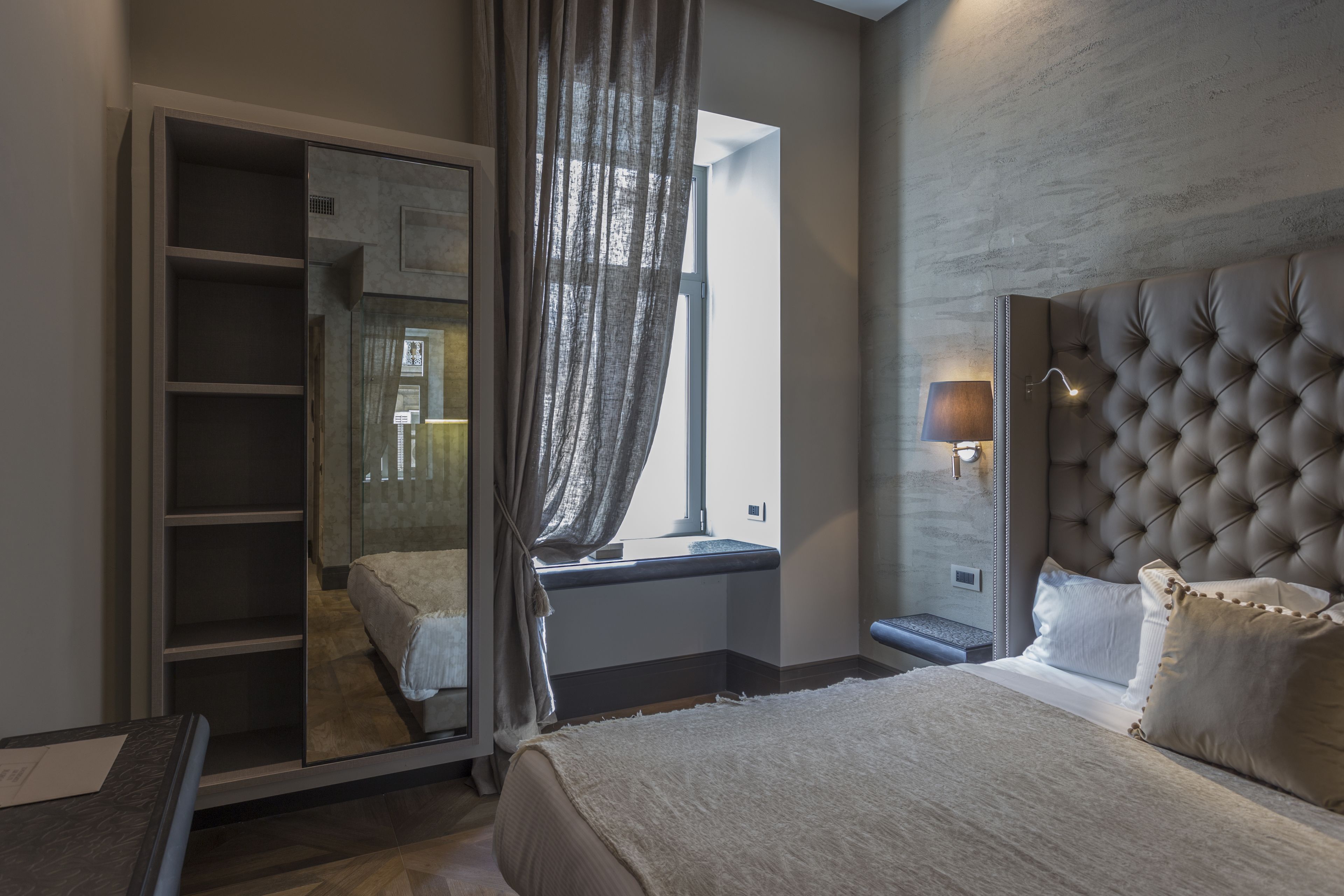 Quarto com cama grande, guarda-roupa, secretária e janela com cortinas.