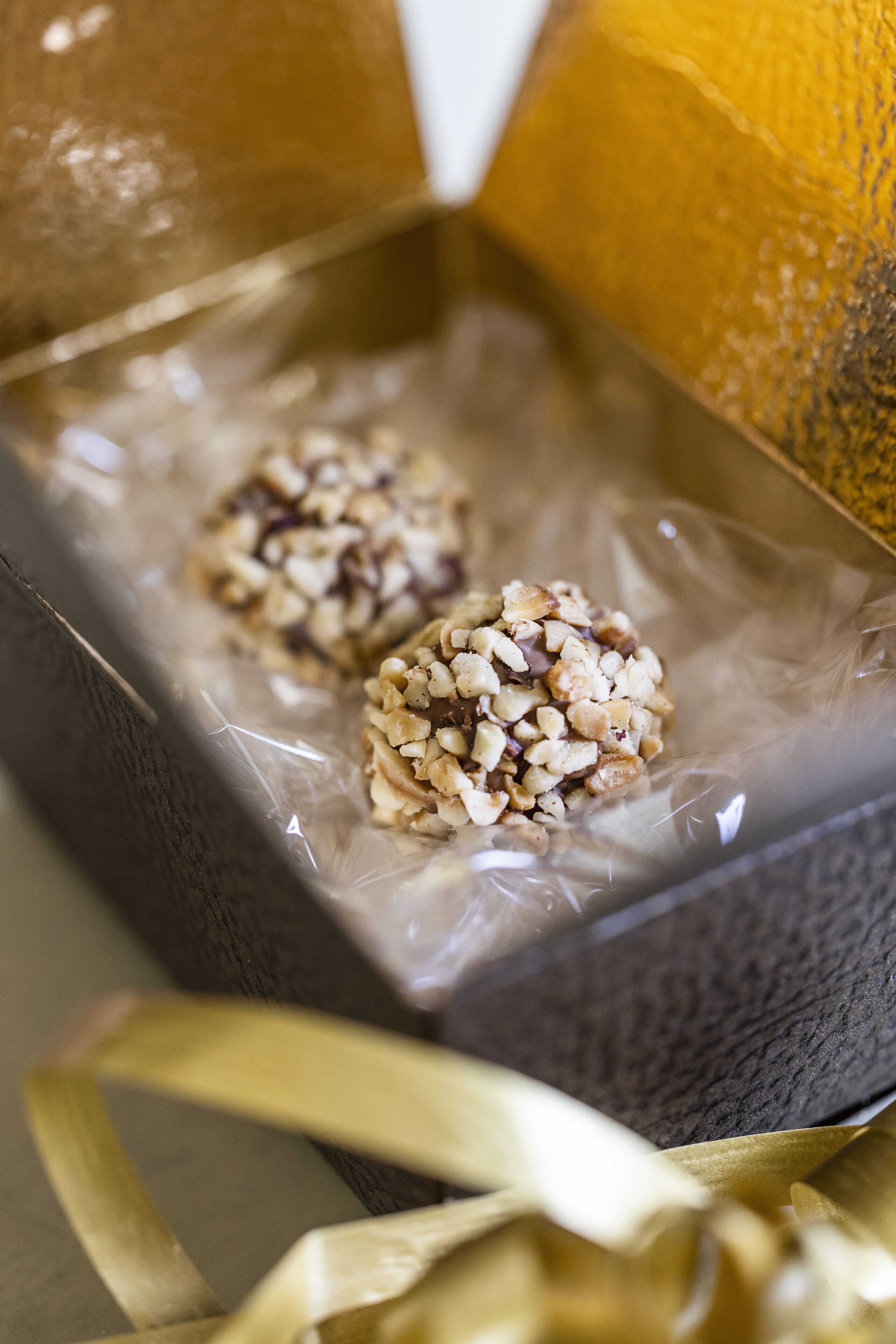Uma caixa com dois itens embalados por dentro, possivelmente comida ou presentes, e um laço dourado.