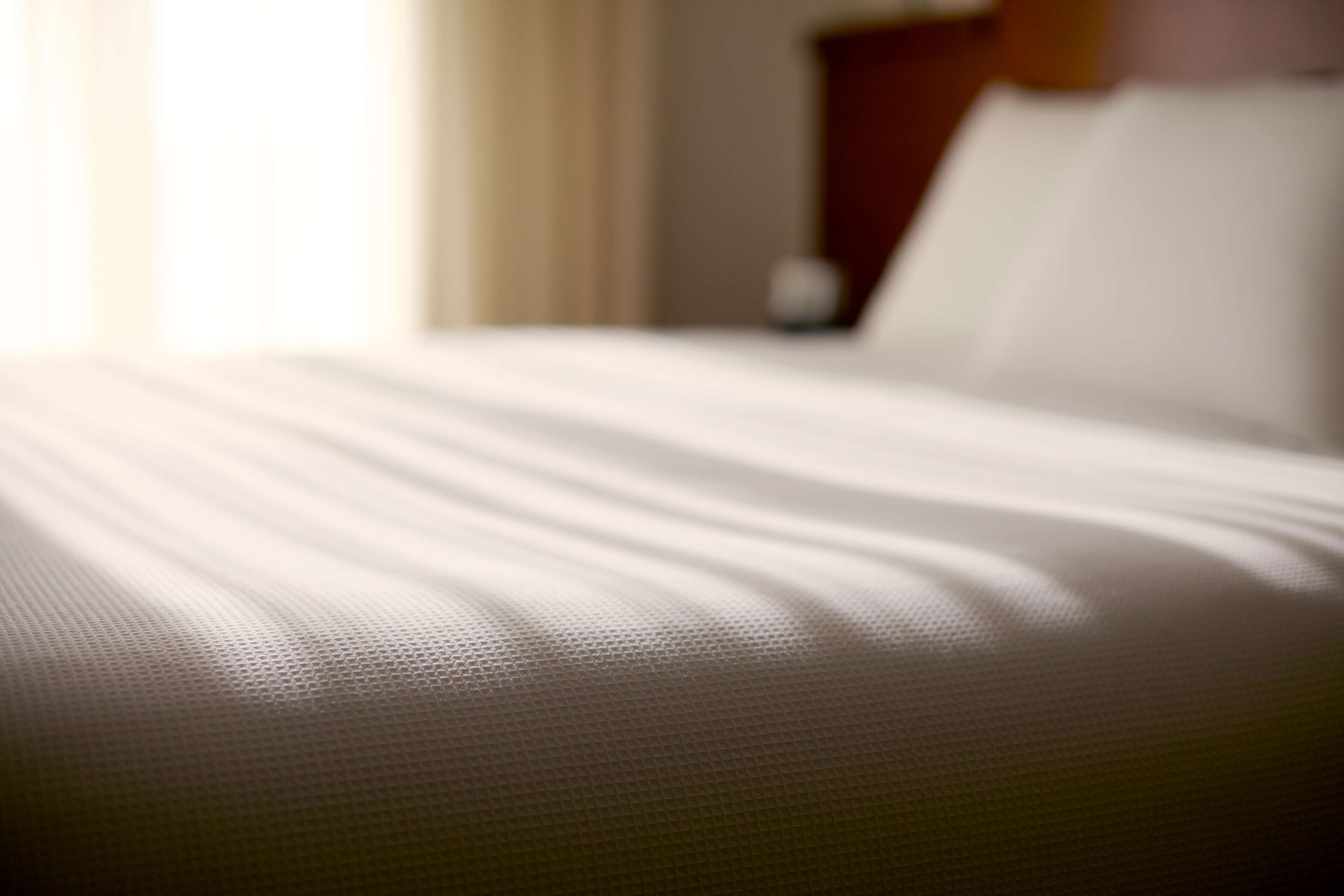 Um close-up de uma cama com cobertura branca texturizada.