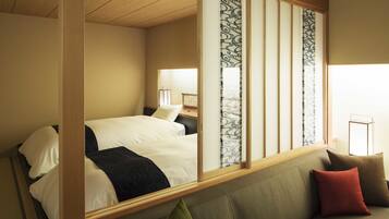 Quarto de hotel com uma cama, um sofá e uma janela com cortinas estampadas.