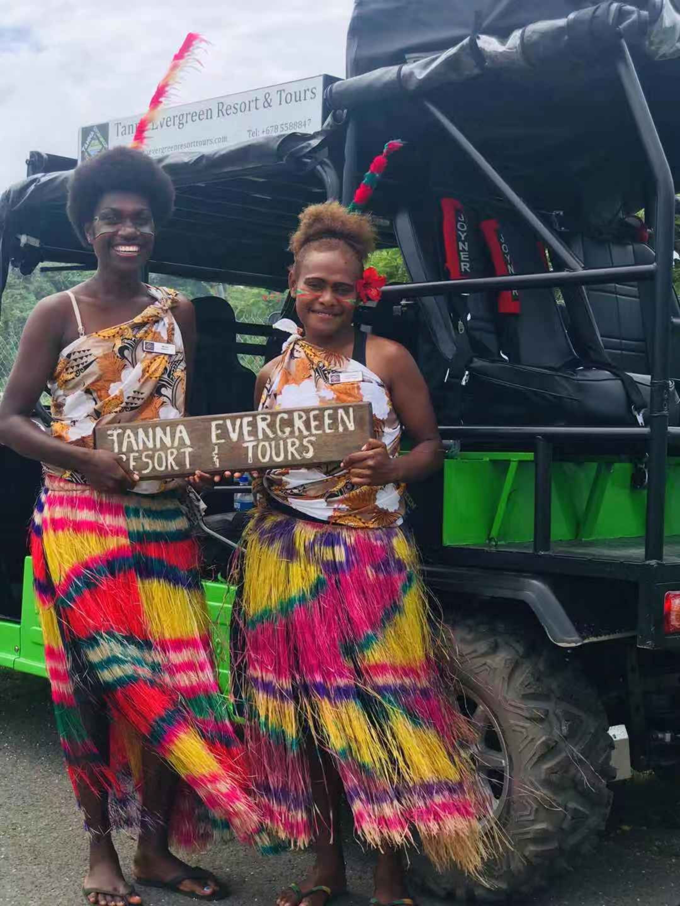 Duas pessoas segurando um letreiro do Tanna Evergreen Resort & Tours.