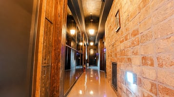Um corredor com piso polido, painéis de madeira em uma lateral e parede de tijolos na outra.