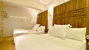 Quarto de hotel com duas camas, paredes de mármore, painéis de madeira e iluminação embutida.