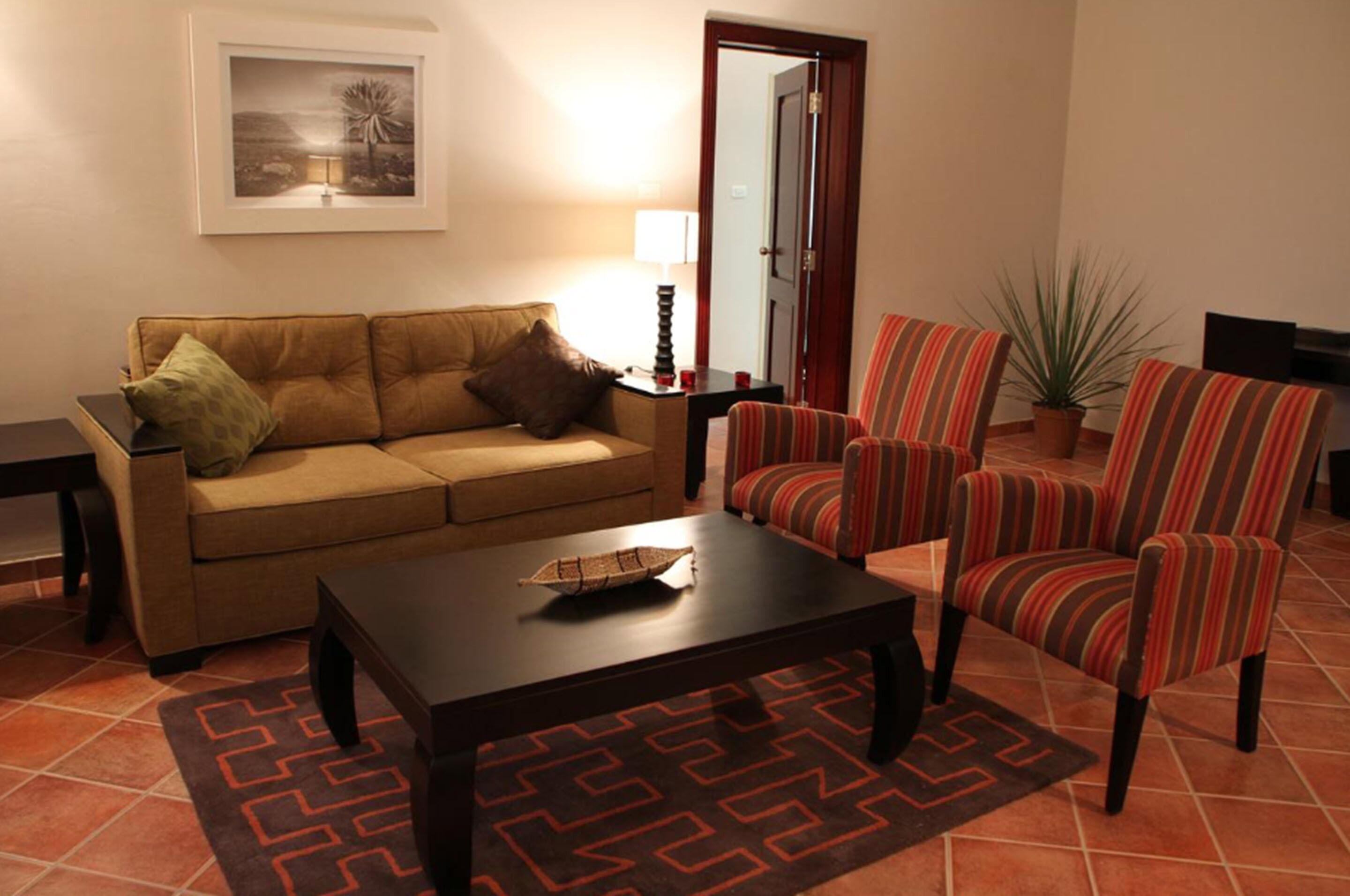 Uma sala de estar com sofá, poltronas, mesa de centro e abajur.