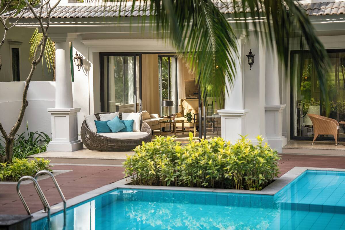 Uma área de piscina com um sofá de vime, uma mesa de jantar e uma cadeira.