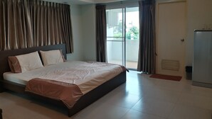 Quarto de hotel com cama, porta de vidro deslizante para uma varanda, ar condicionado e geladeira.