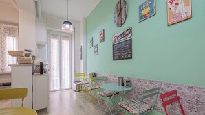 Uma cozinha acolhedora com área de jantar, apresentando uma parede verde, piso de madeira e diversos utensílios e objetos de decoração.