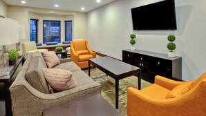 Uma sala de estar moderna com sofá, poltronas, mesa de centro e televisão de tela plana na parede.