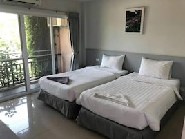 Quarto de hotel com duas camas, varanda e vista, e uma moldura na parede.