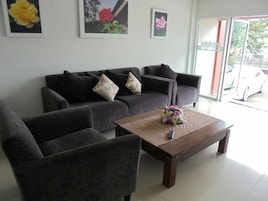 Uma sala de estar com sofá e poltronas, uma mesa de centro com um arranjo floral e arte floral emoldurada na parede.