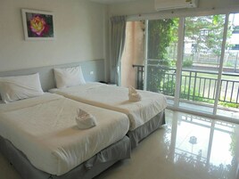 Quarto de hotel com duas camas, uma janela ampla com vista para o verde e um quadro na parede.
