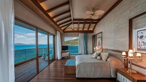 Um quarto espaçoso com uma cama grande, televisão e vista para o mar.