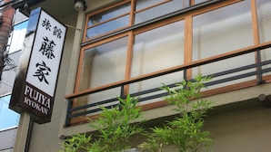 Um edifício com uma placa que diz "FUJIYA RYOKAN" e uma janela com moldura de madeira e tela.