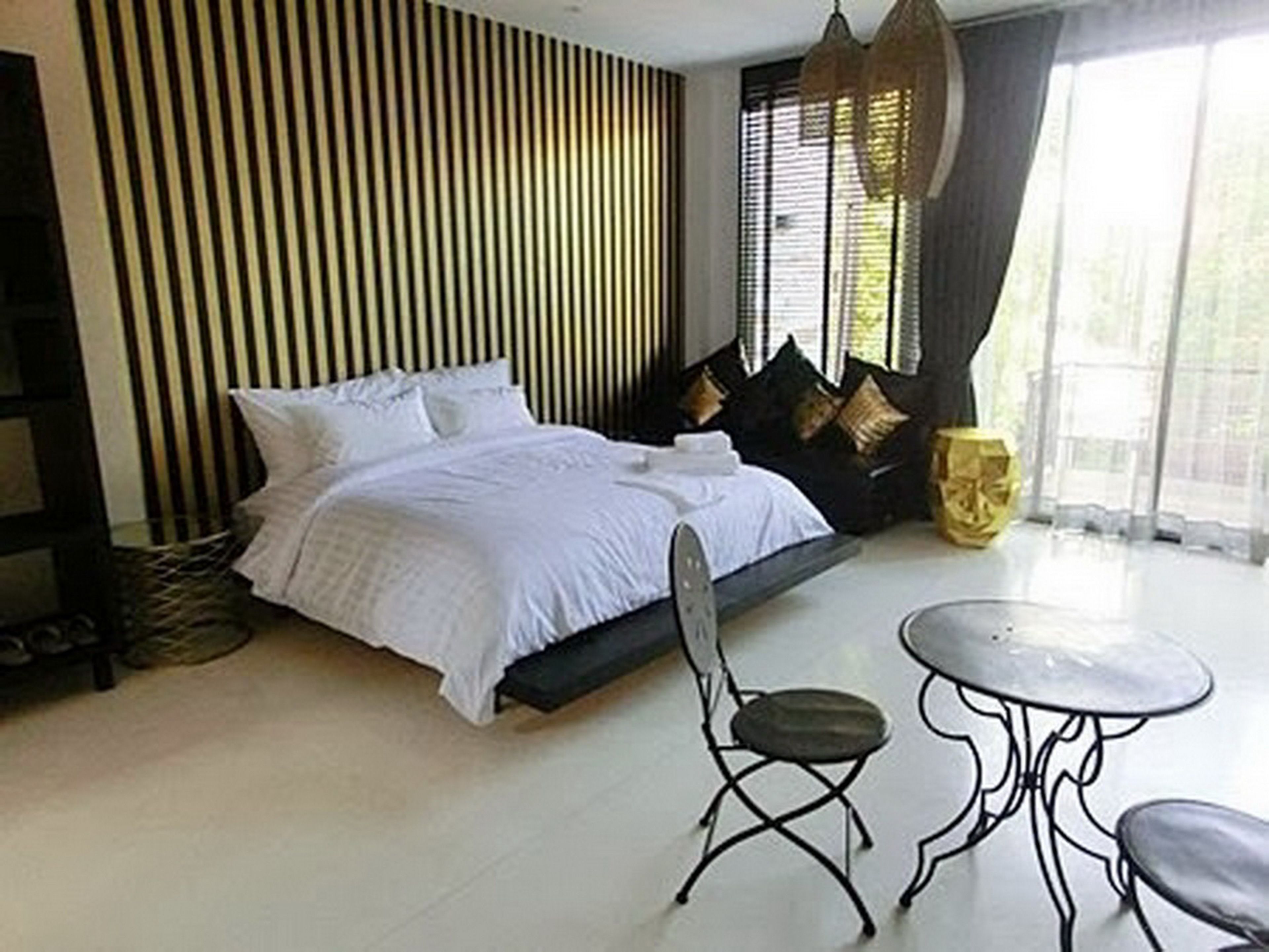 Quarto moderno com uma cama, uma mesinha e uma cadeira.