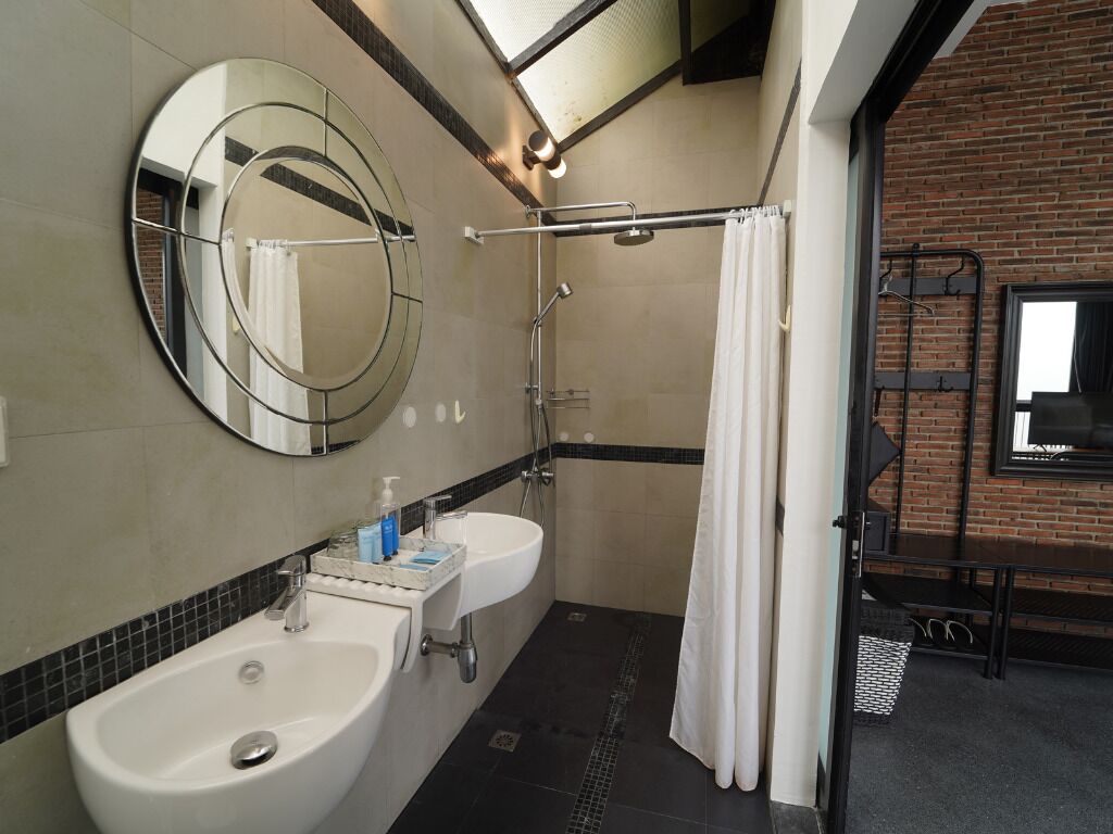 Uma casa de banho moderna com uma grande pia, um espelho, chuveiro com porta de vidro e chão em mosaico preto e branco.