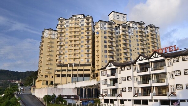 Um hotel de vários andares com arquitetura tradicional, com varandas e um letreiro grande com a palavra 'HOTEL'.