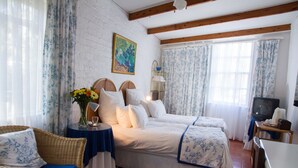Quarto com uma cama grande, duas mesas de cabeceira, televisão e janela com cortinas.