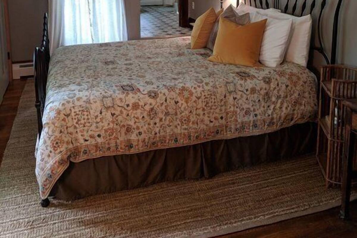 Um quarto com uma cama, uma mesa de cabeceira, uma luminária e uma cadeira.