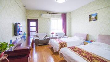 Quarto de hotel com duas camas, uma escrivaninha com computador, uma cadeira, janela com cortinas e unidade de ar condicionado.