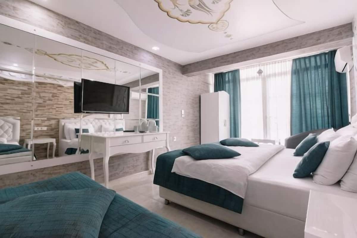 Quarto com cama, escrivaninha, televisão e guarda-roupa.